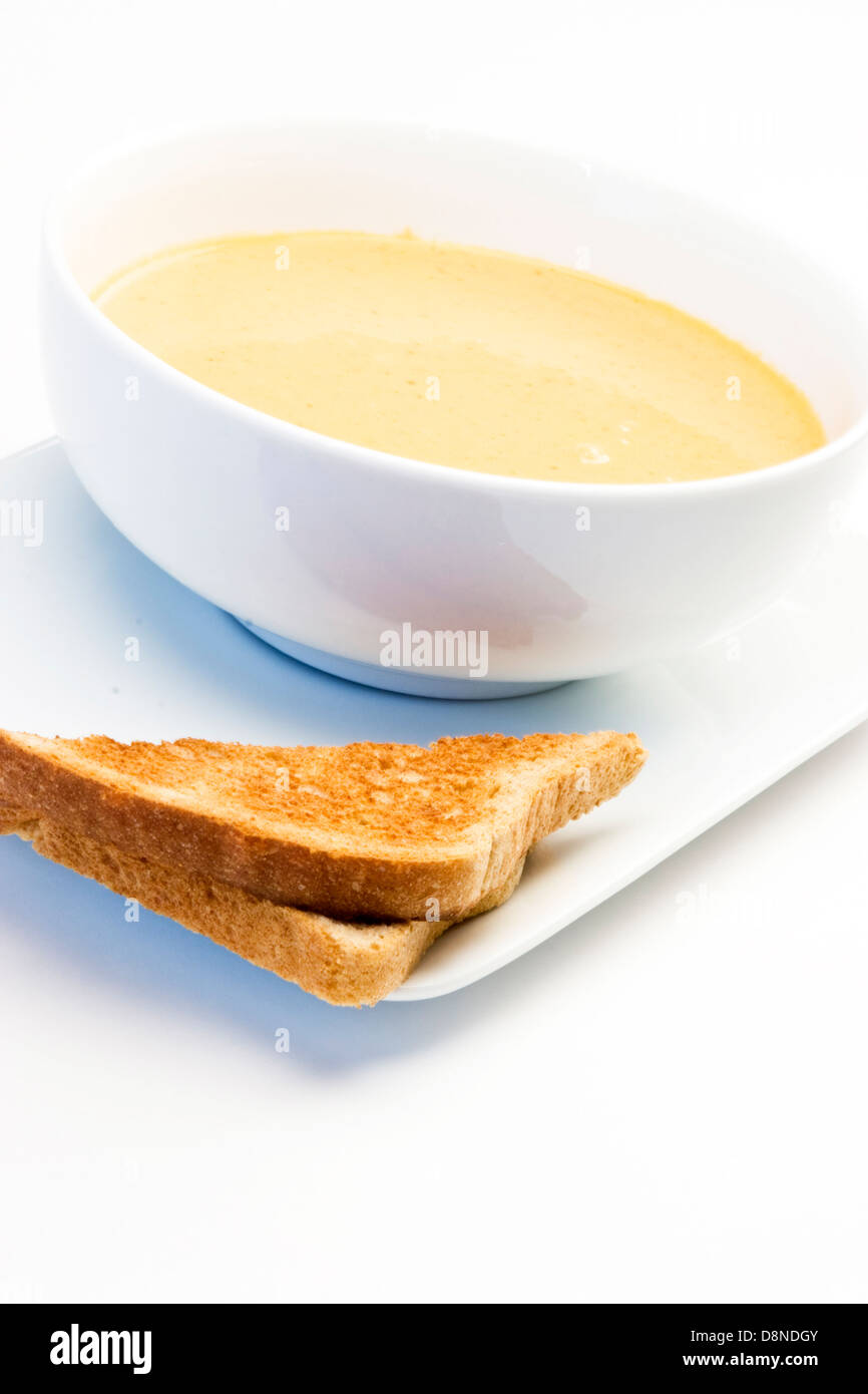 A bowl of tomato soup and toast is seen against a white background ...
