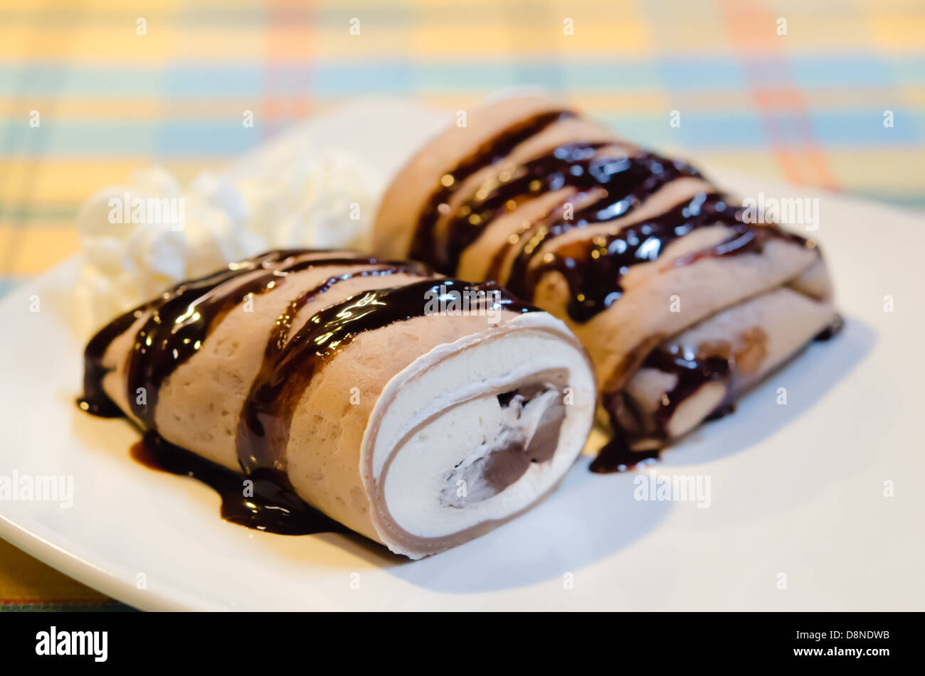 crepe rolls filled with white cream , topping with chocolate syrup ...