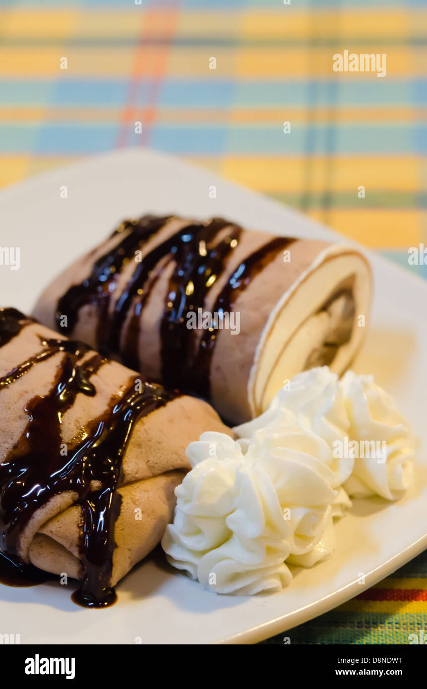 close up chocolate crepe rolls topping with chocolate syrup served with ...