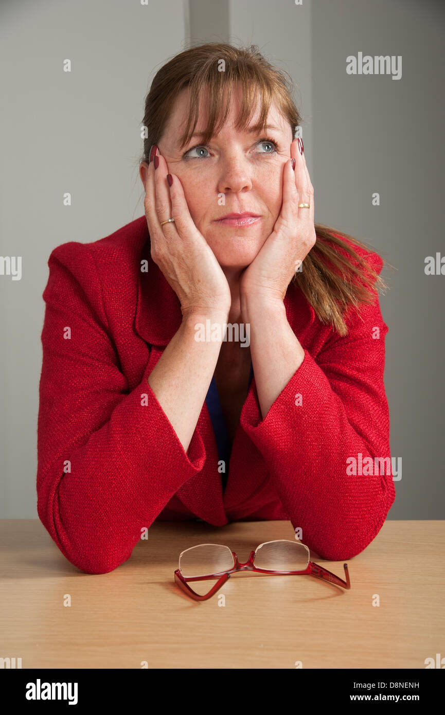 Woman at desk resting her head in cupped hands Stock Photo - Alamy