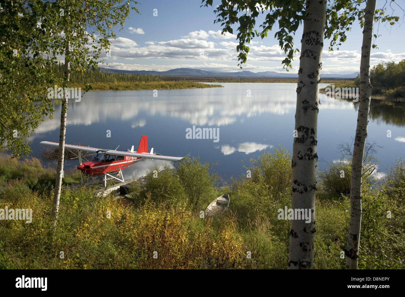 A water jet plane is seen on the shore of a lake near a small boat. The ...