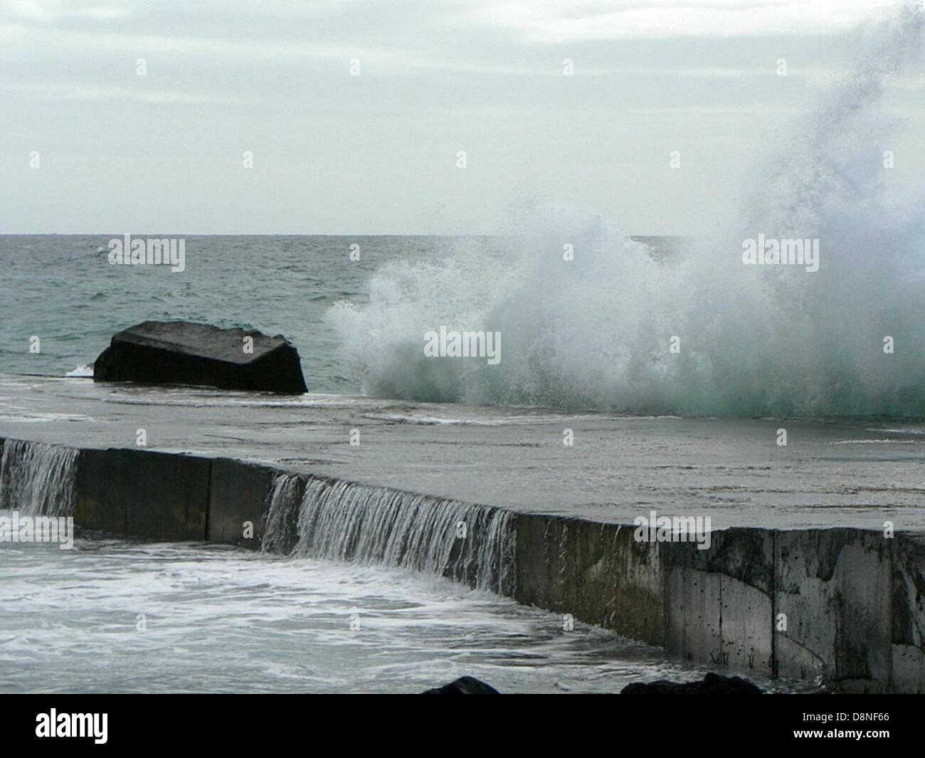 Waves crash against a pier, capturing the energy and motion of the ...