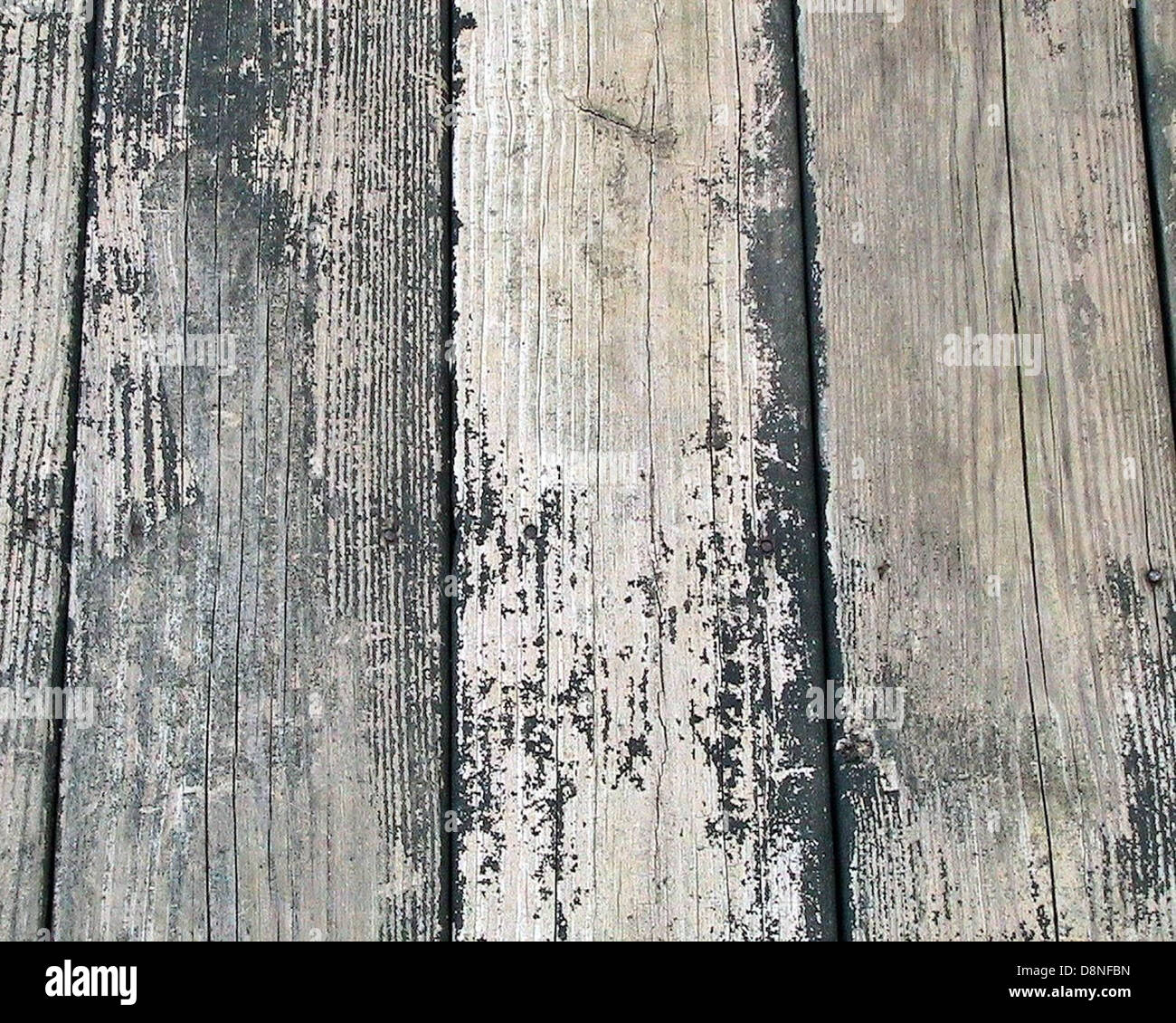 A weathered wooden decking surface showing signs of wear from exposure ...