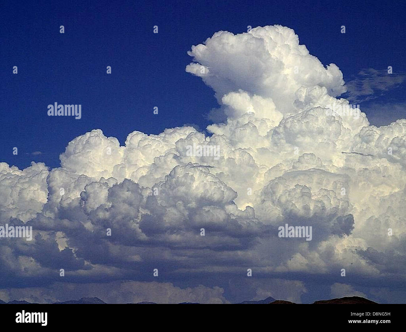 White cumulus clouds drift across a bright blue sky, often associated ...