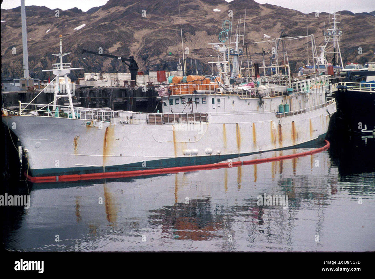 A white, weathered ship with noticeable rust spots docked in a marine ...