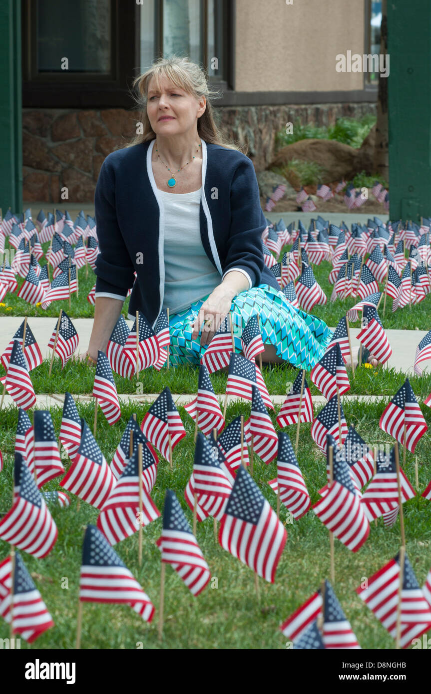 Woman weeping while holding a United States flag and sitting in field ...