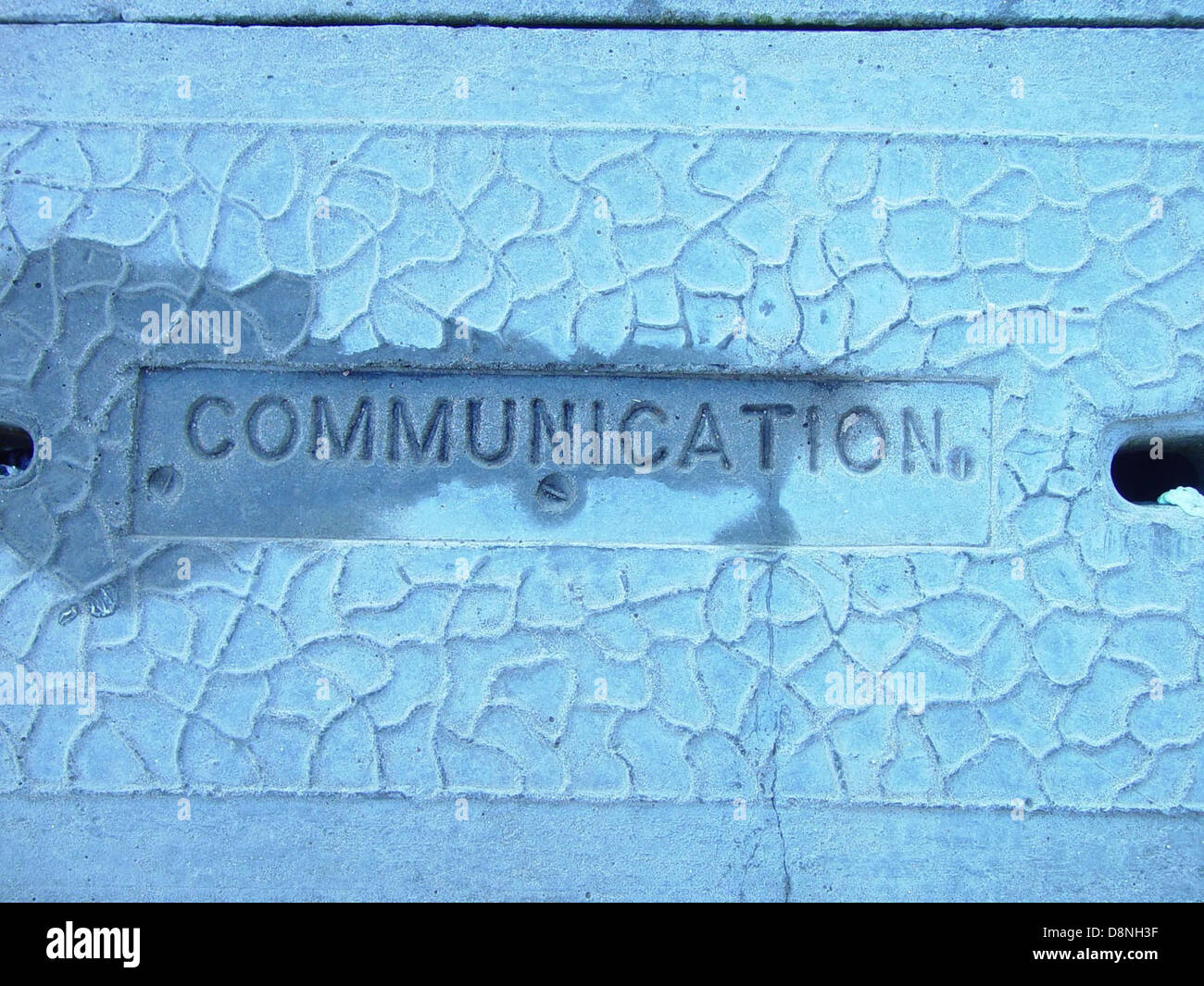This image shows a word recessed into a concrete cover, likely a ...