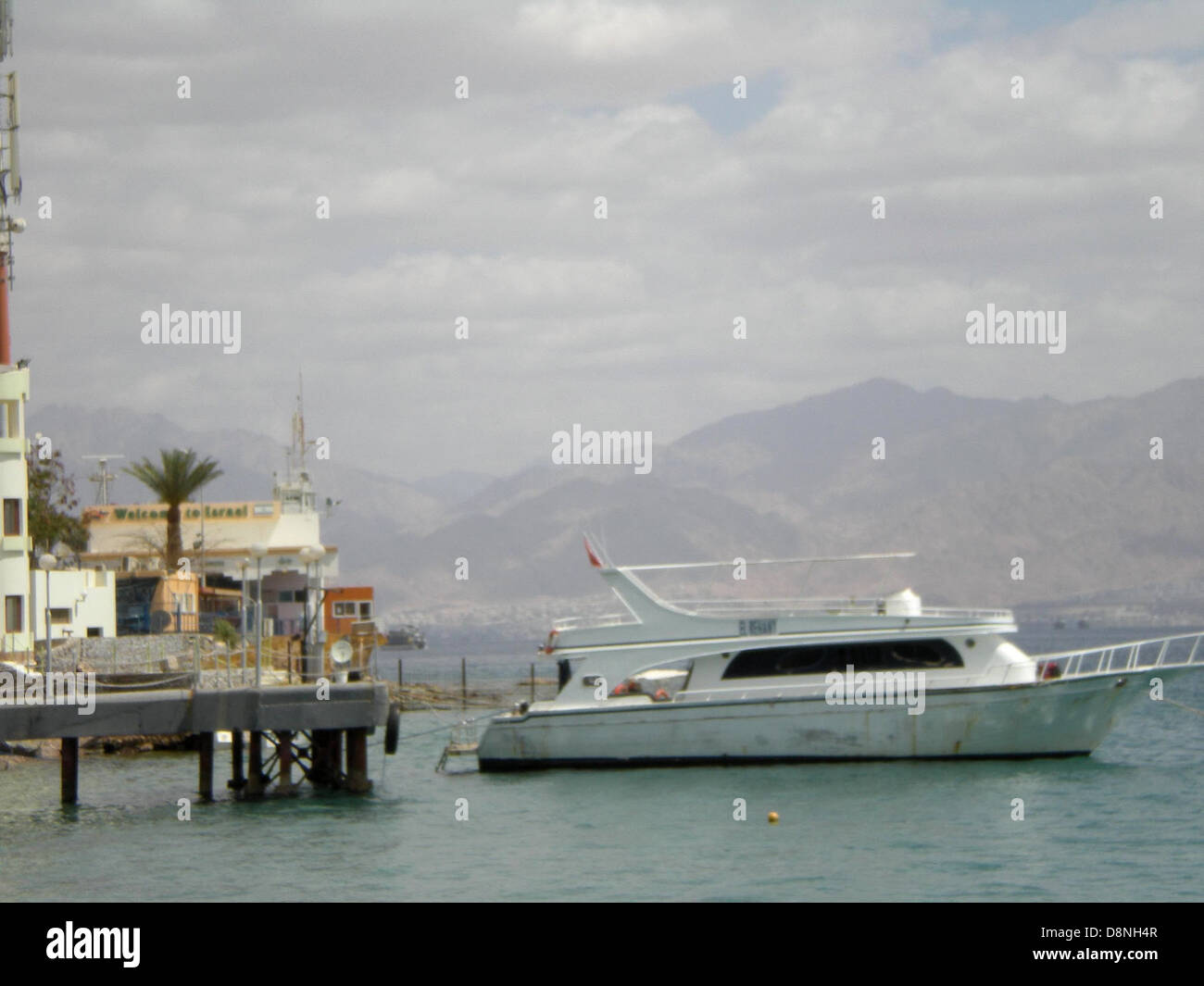 A luxury yacht is docked in a calm harbor, with the clear waters ...