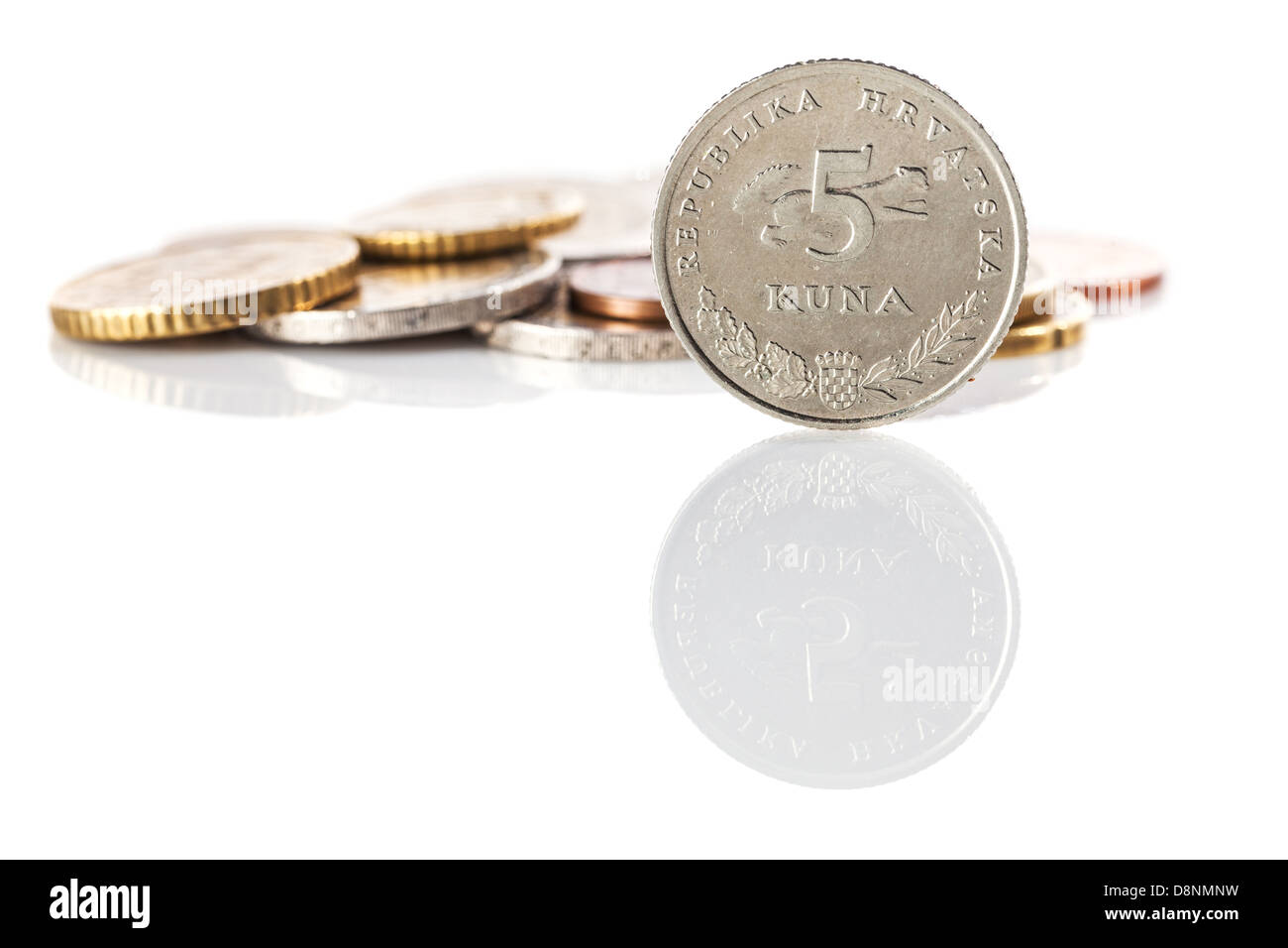 A standing 5 kuna coin - Croatian currency - in front of the heap of ...