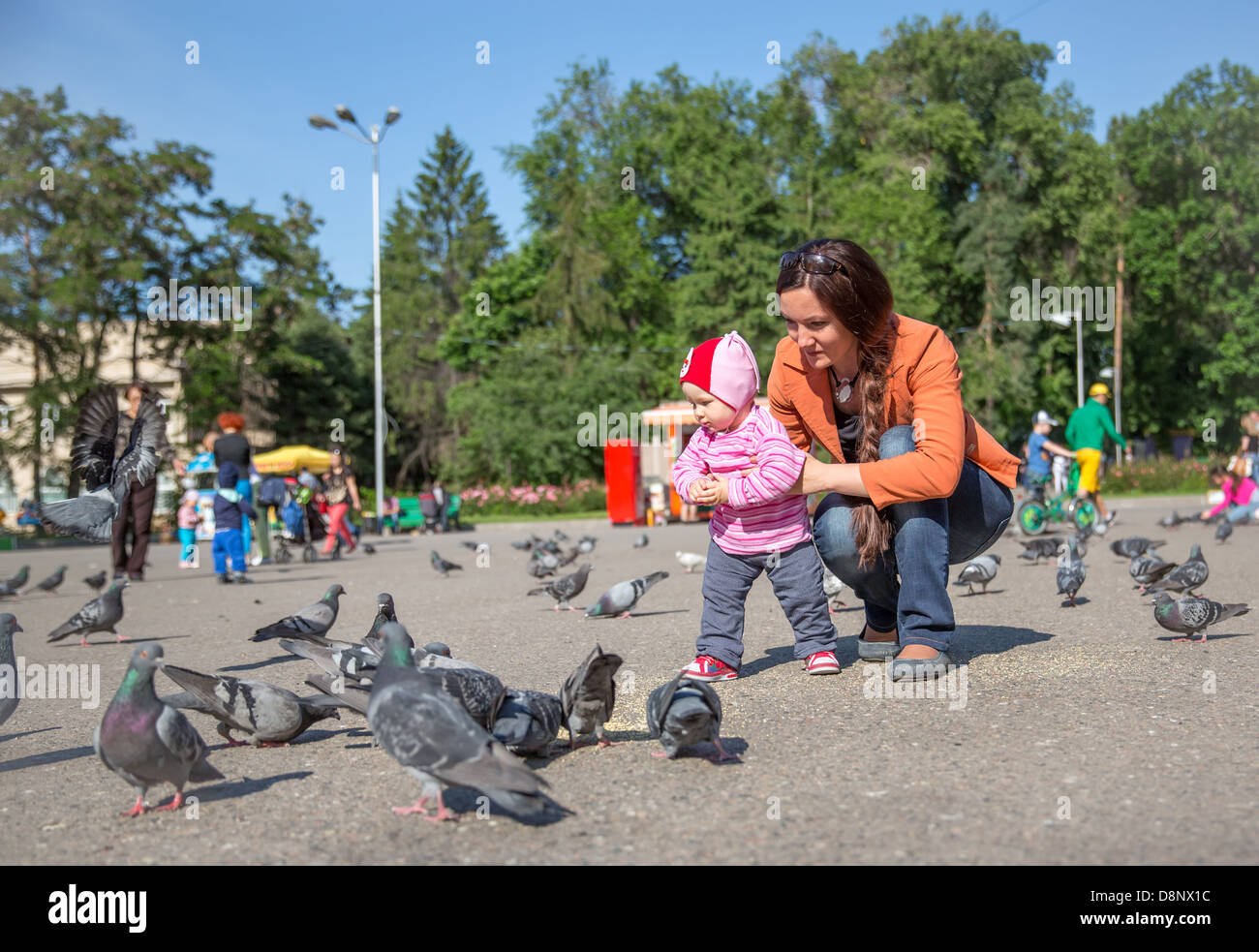 child girl and mum playing with doves in the city street Stock Photo ...