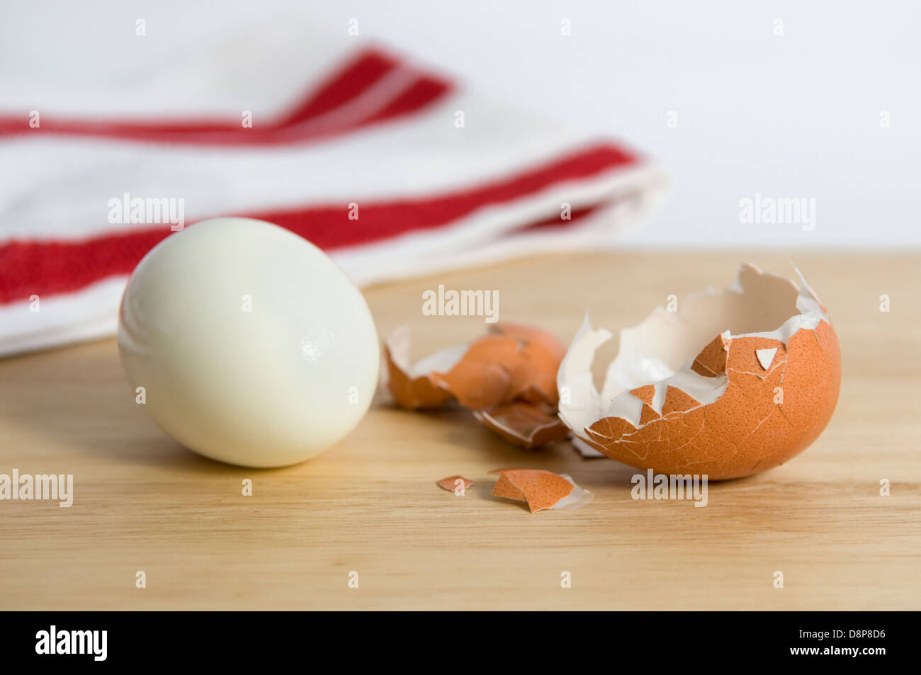 Hard Boiled Egg Cut In Half With Egg Shell On Wooden Chopping Board