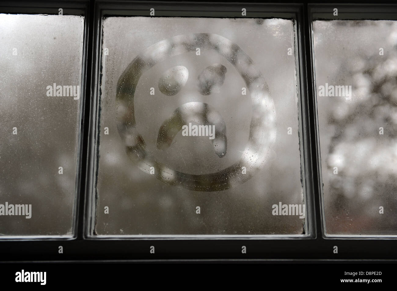 sad smiley face drawn in condensation on a window pane uk Stock Photo ...