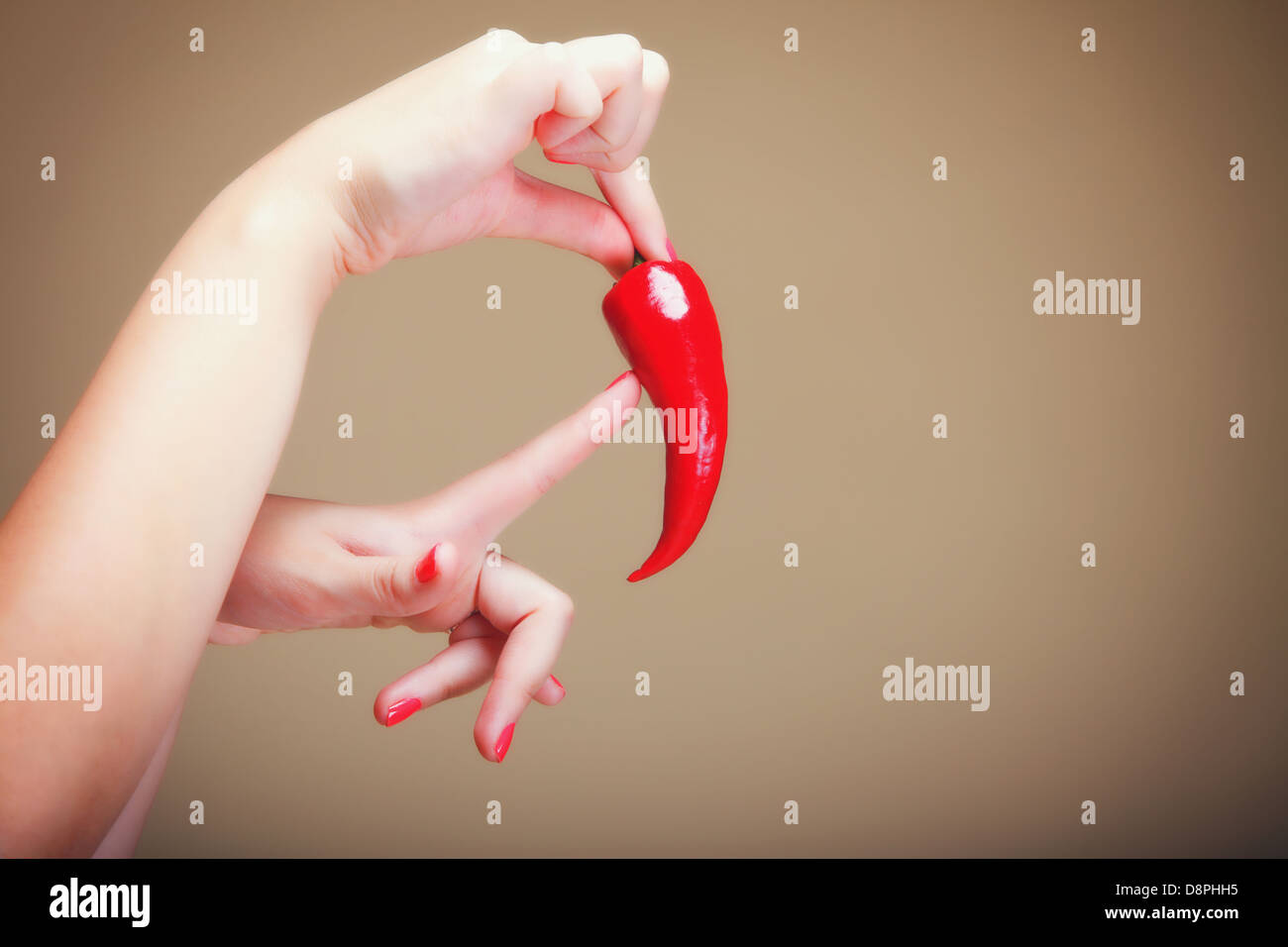 chili pepper in female hand brown background Stock Photo - Alamy
