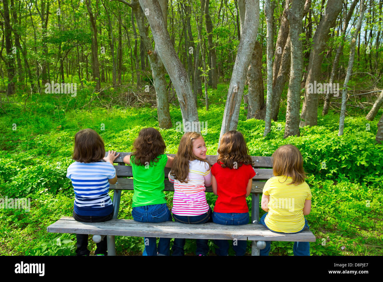 Children sister and friend girls sitting on park bench looking at ...