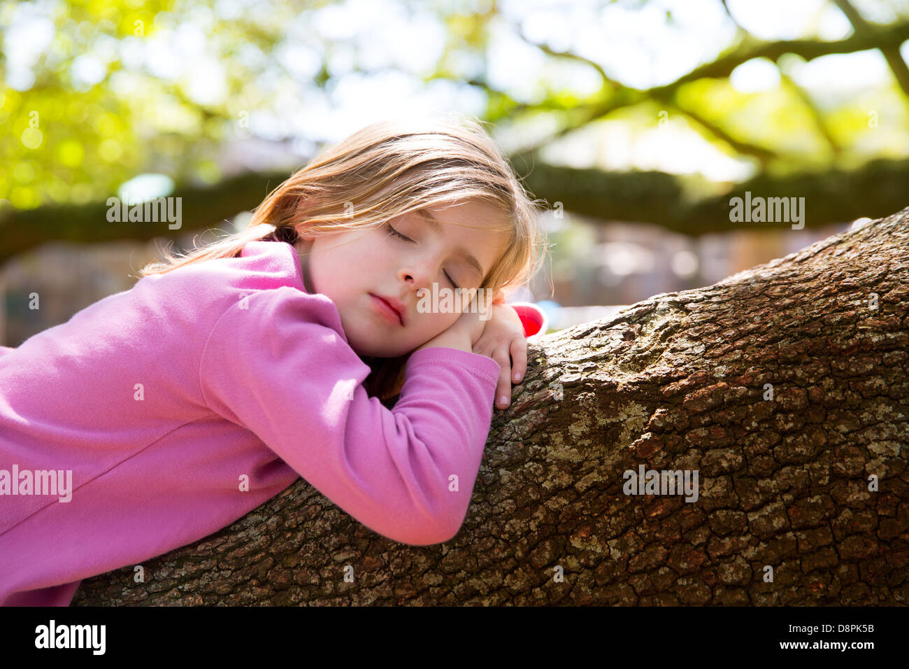 Blond children kid girl having a nap lying on a tree branch Stock Photo ...