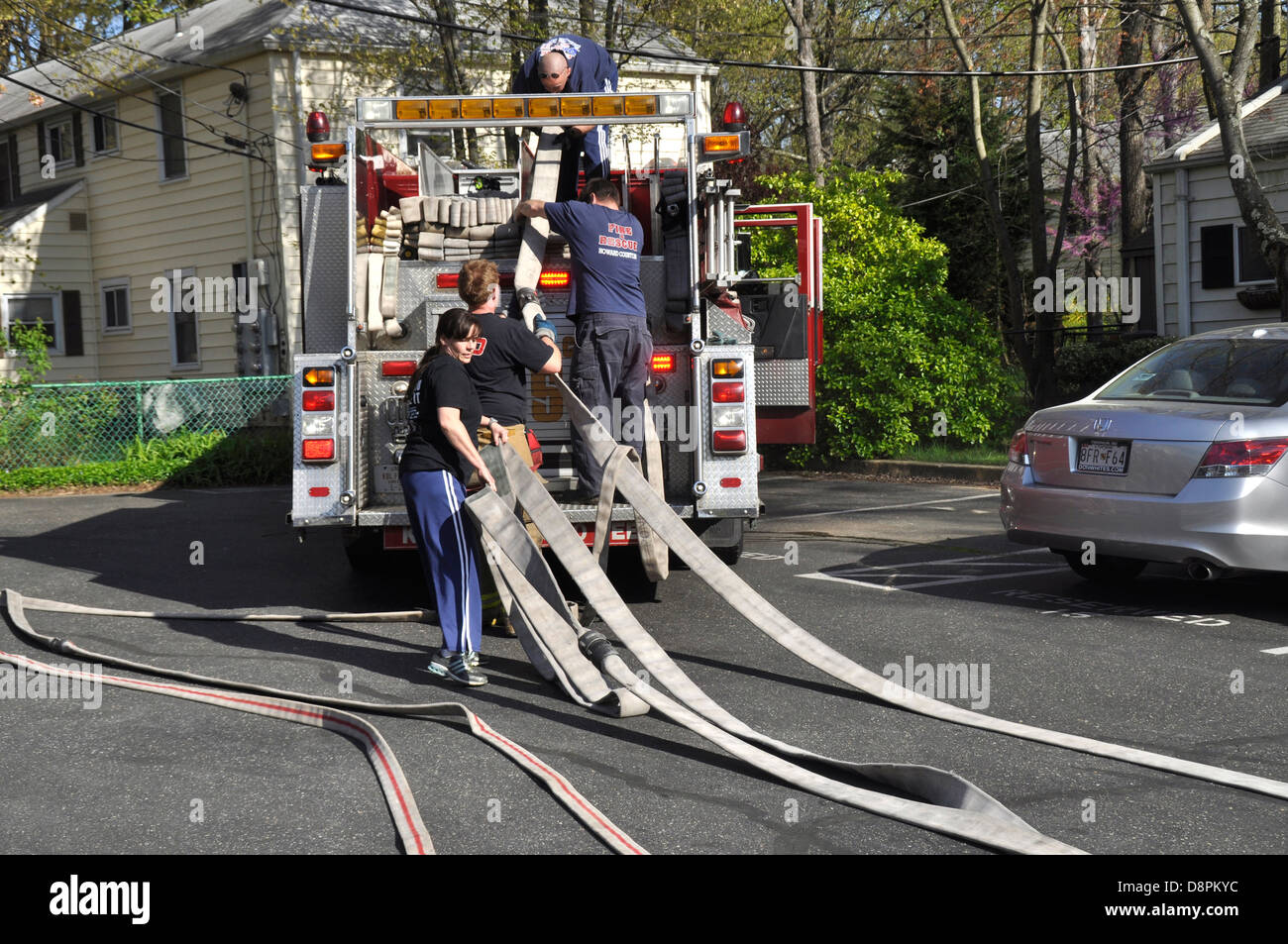 Firefighters racking up hose after extinguishing a fire Stock Photo - Alamy