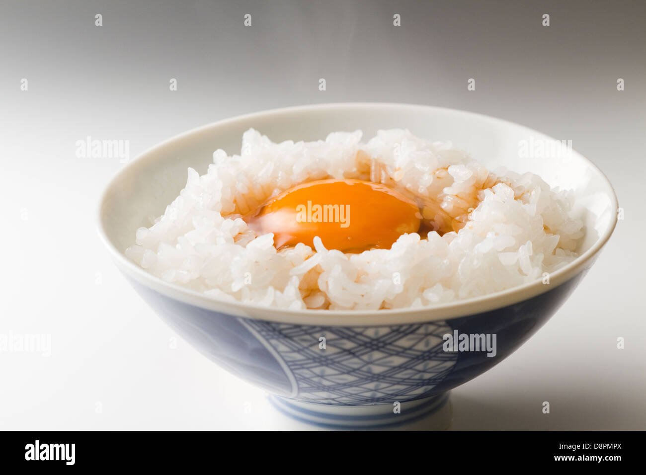 Raw egg on rice Stock Photo - Alamy