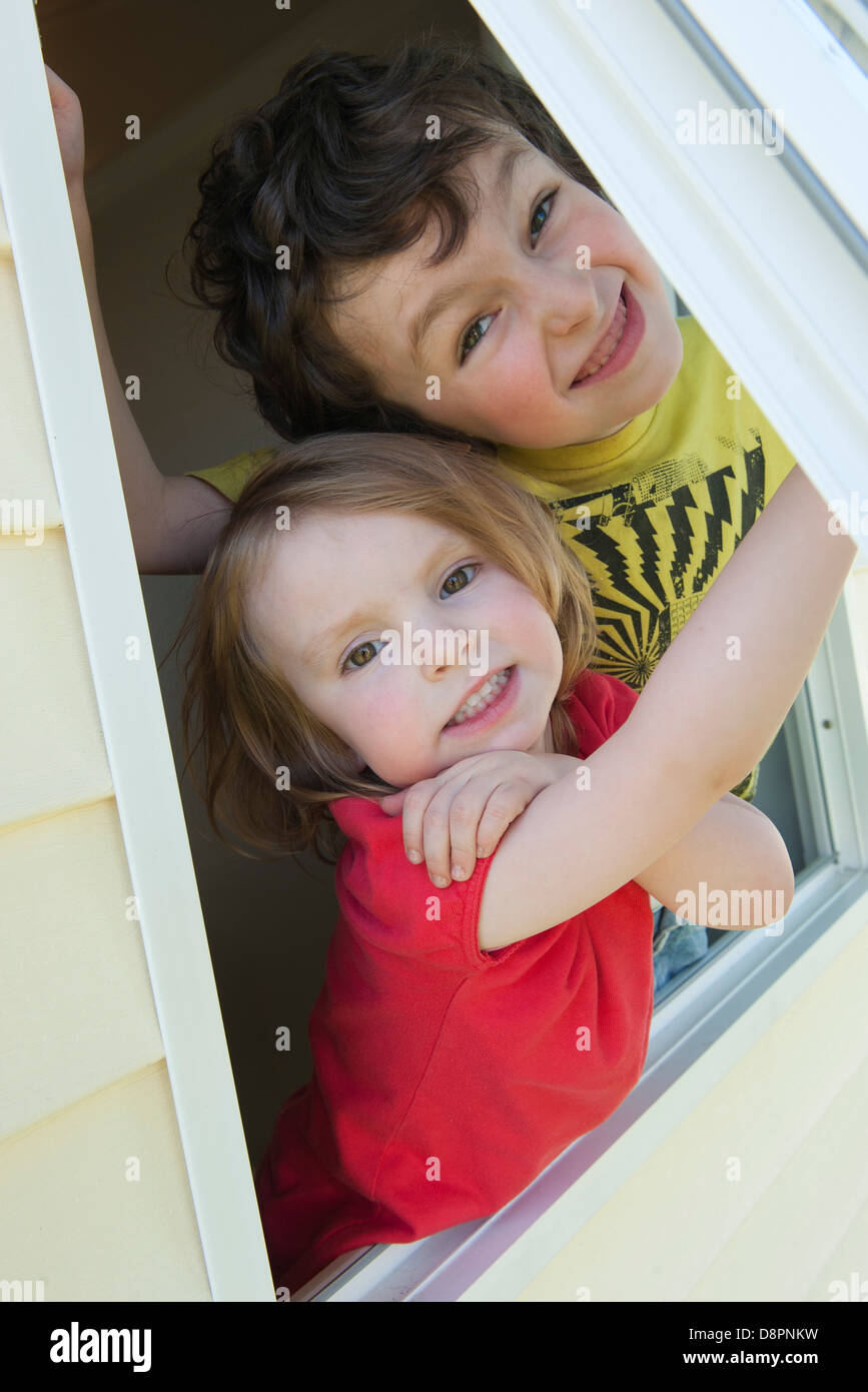 Young siblings looking out open window, portrait Stock Photo - Alamy