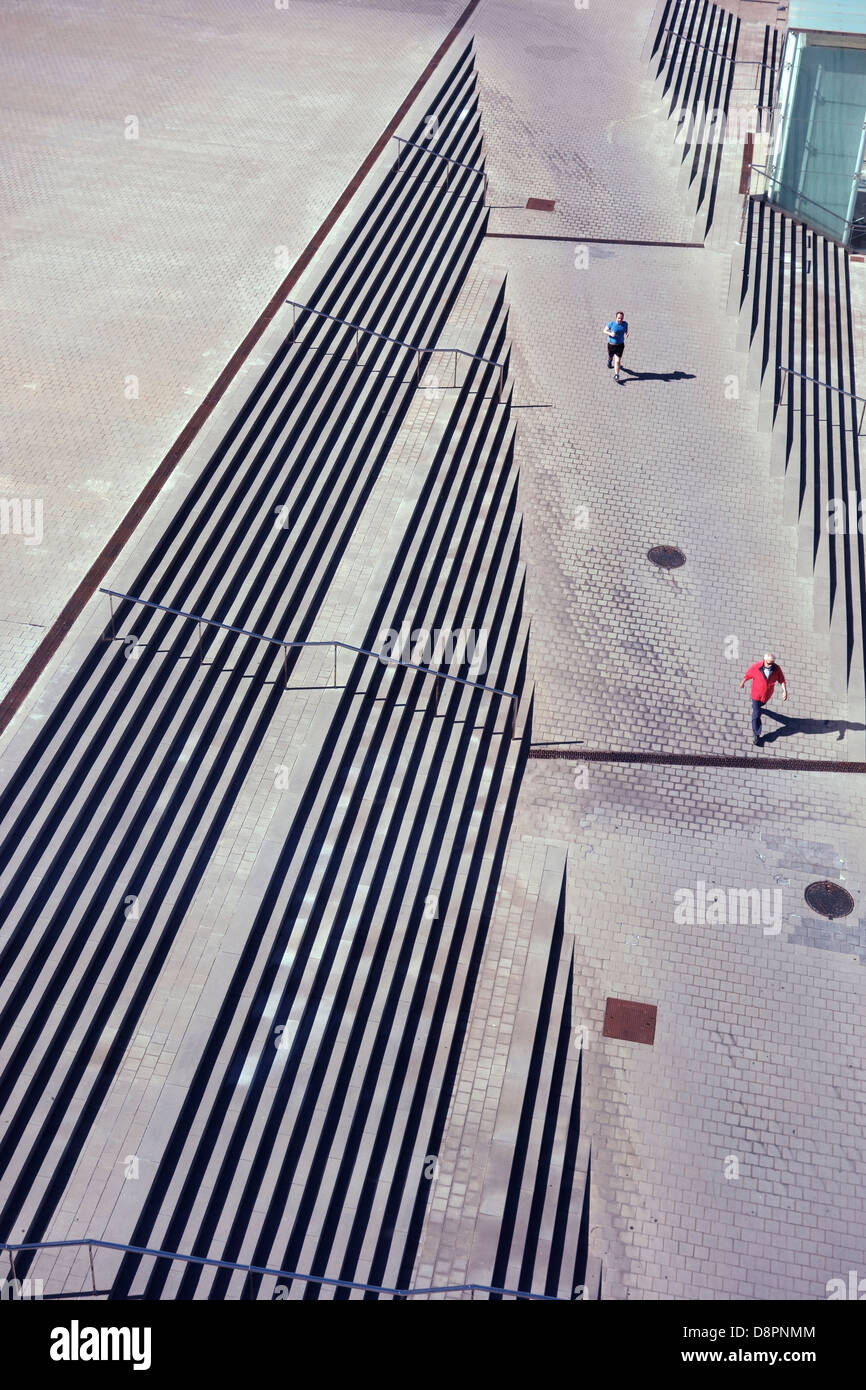 Looking down to a man walking and a man running along a path through ...