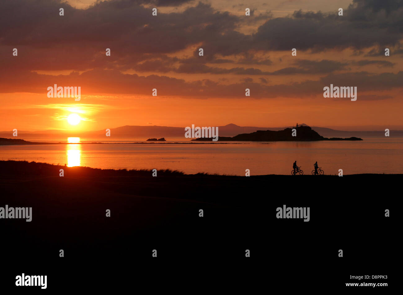 Sunset view of cyclists looking over the Firth of Forth to Fidra Island ...