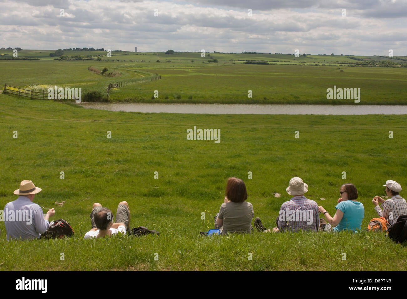 A group of country ramblers rest for lunch on the sea defence ...