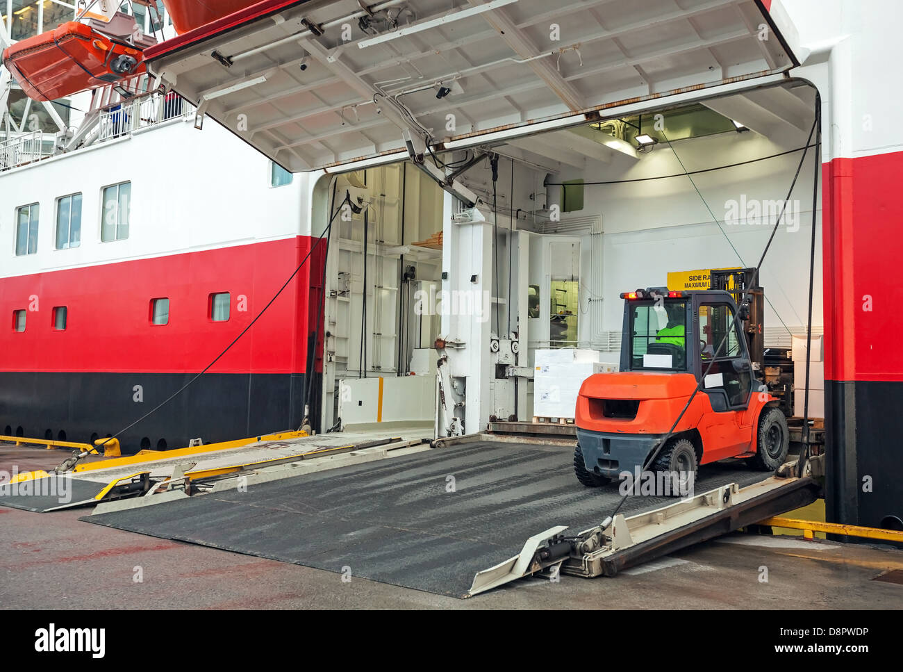 Lift truck unloads big passenger ferry through opened side ramp Stock ...