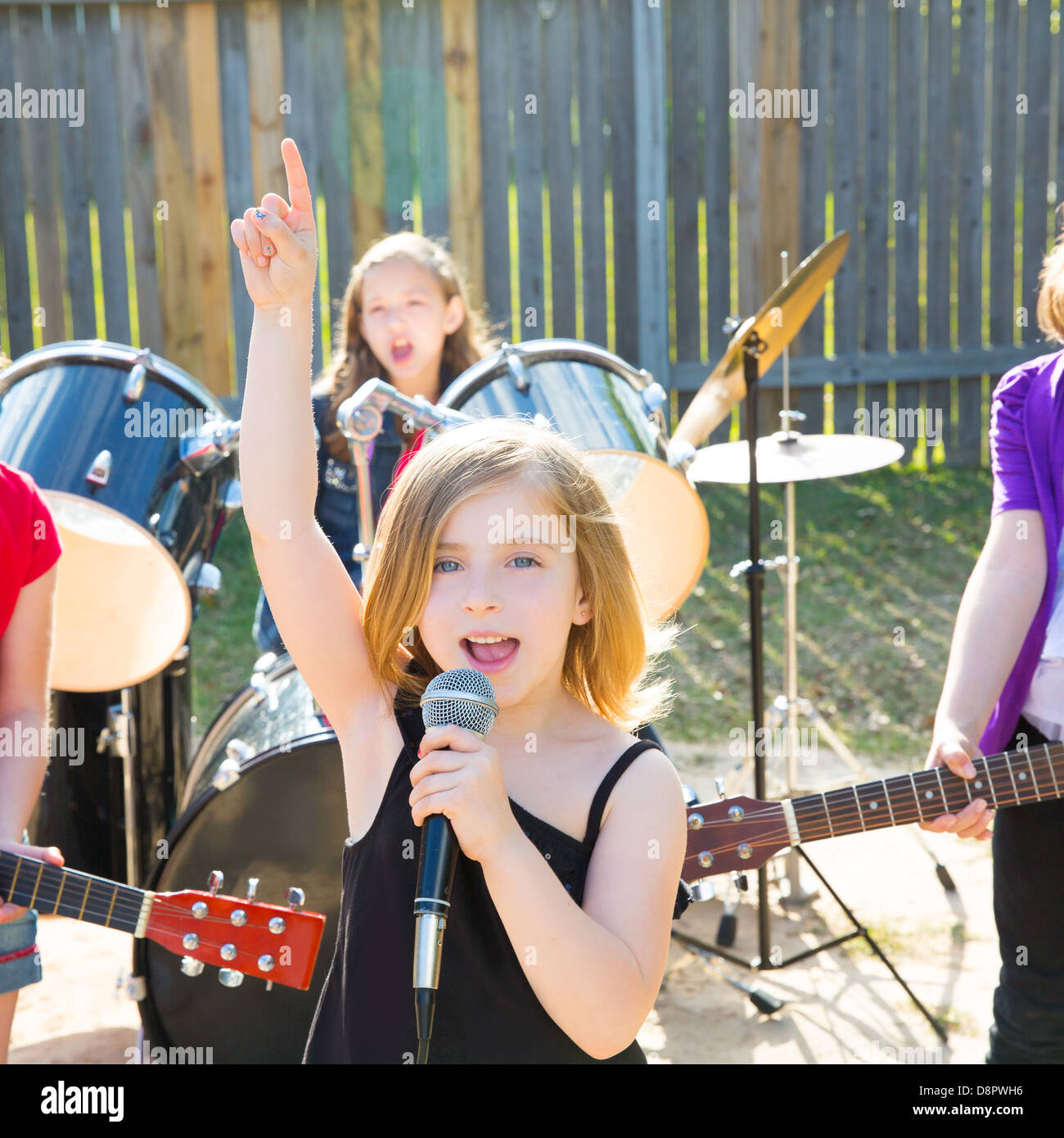 Blond kid singer girl singing playing live band in backyard concert ...
