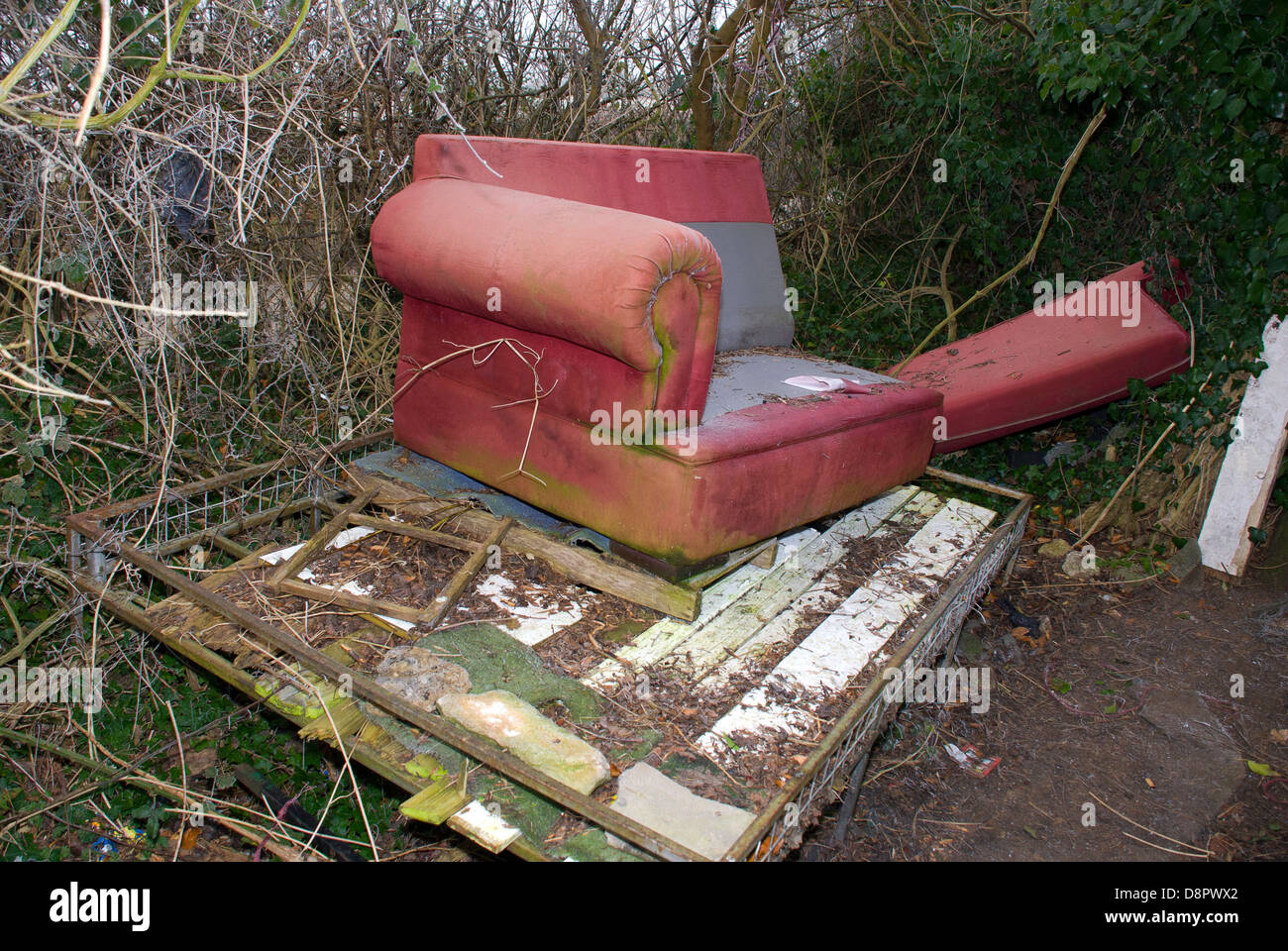 An abandoned red couch in a rural, icy wooded scene Stock Photo - Alamy