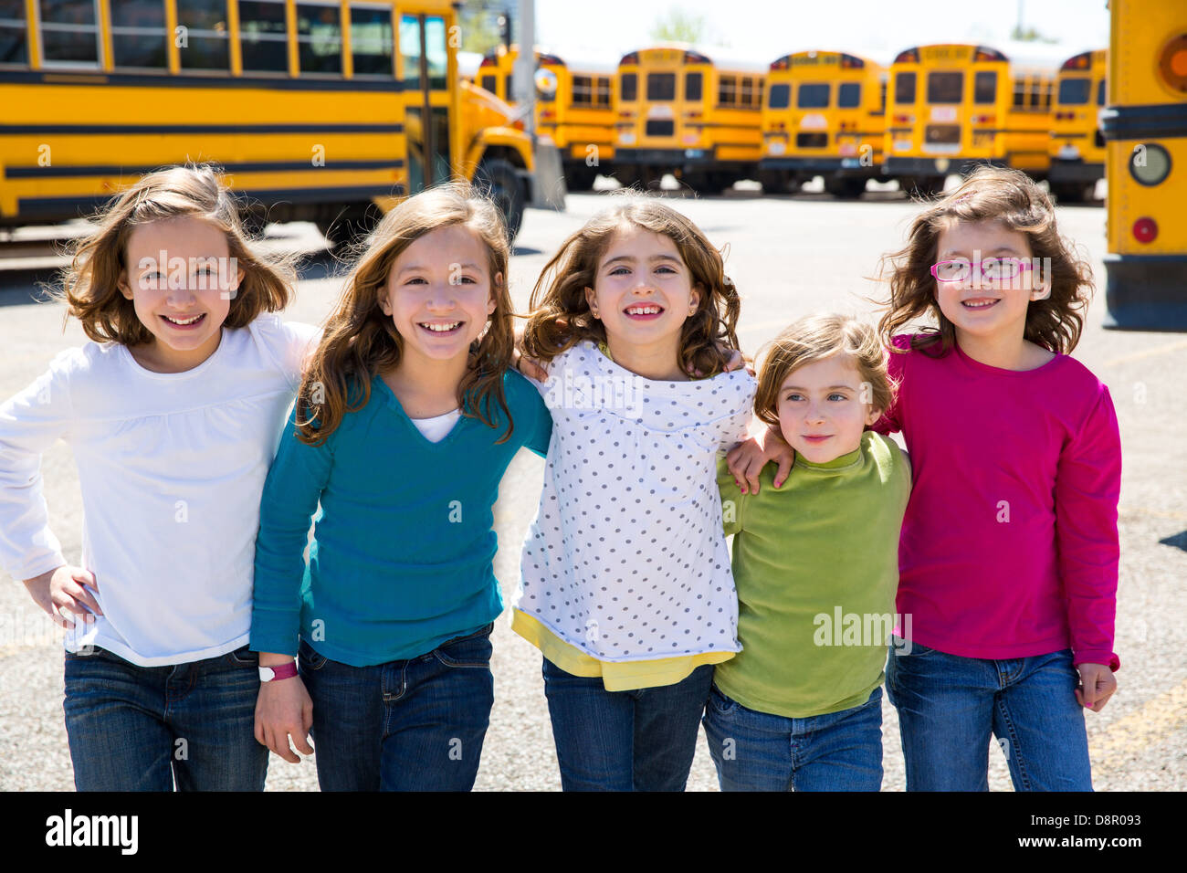 school girls friends sisters in a row walking from yellow school bus ...
