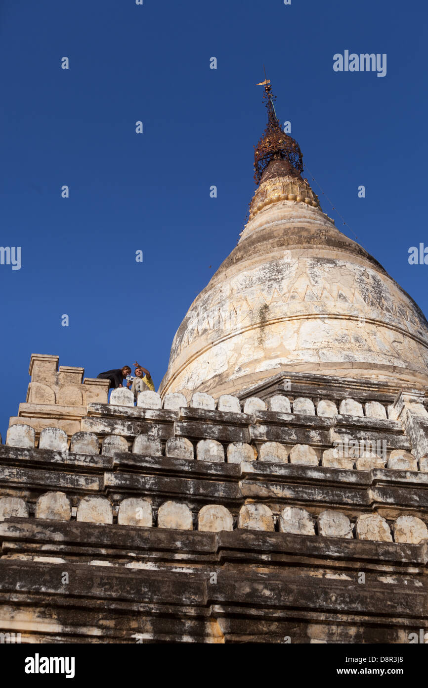 High on an ancient temple parapet two tourists consult the map and look ...