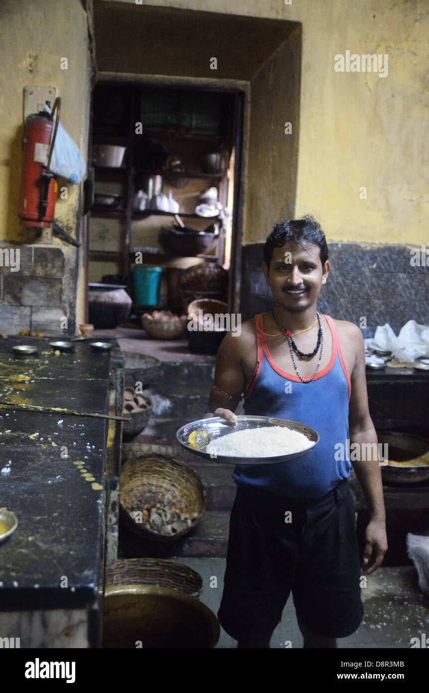 Waiter holding salver with rice standing by kitchen, Sidheshwari Ashram ...