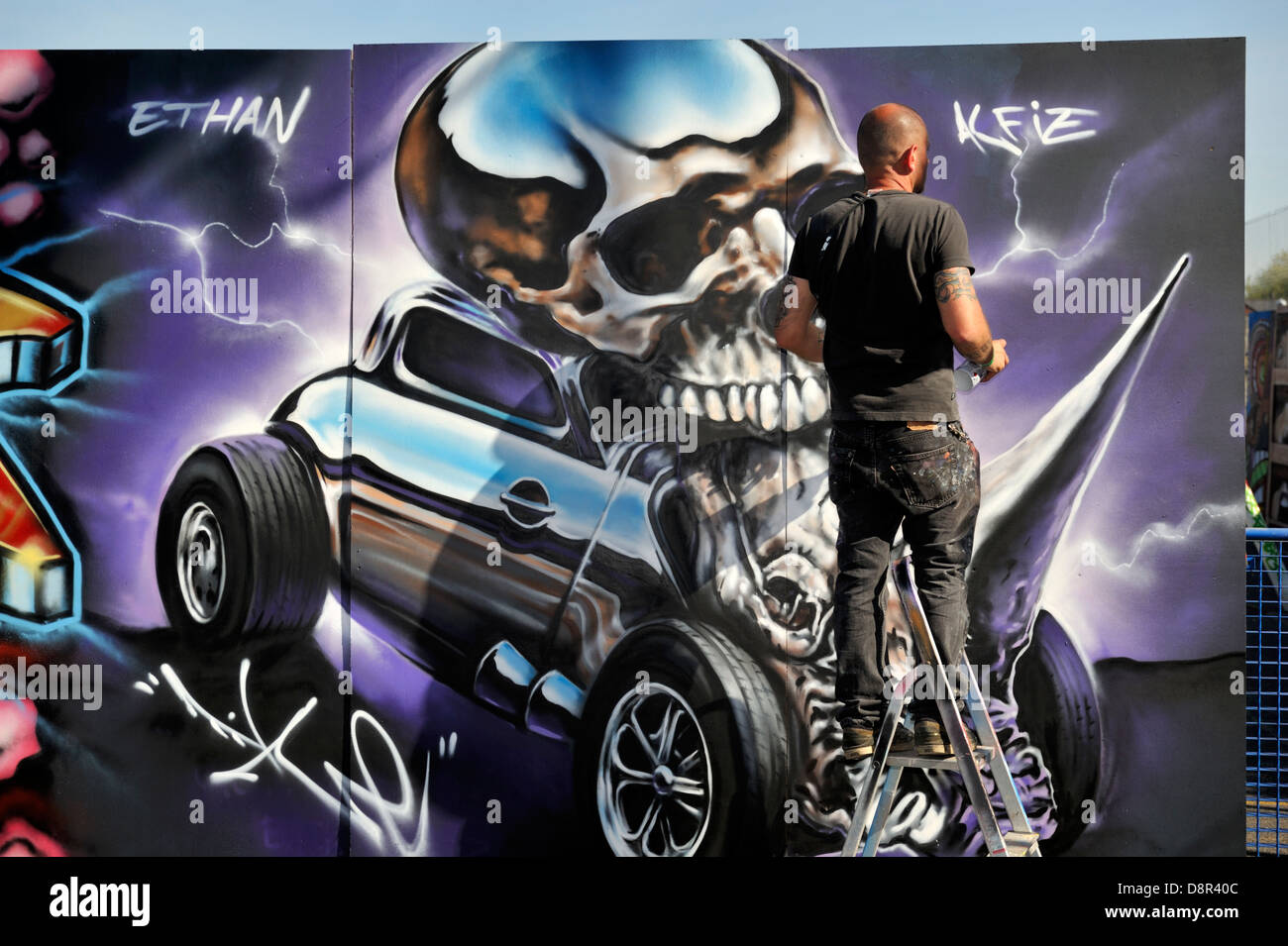 Graffiti artist "Title" painting on display boards at Upfest festival ...