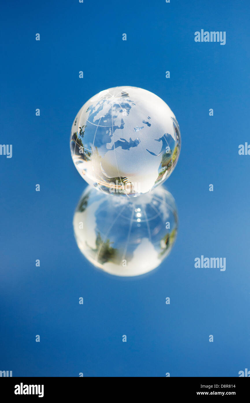 Crystal Glass globe / earth / world on a mirror reflecting blue sky ...