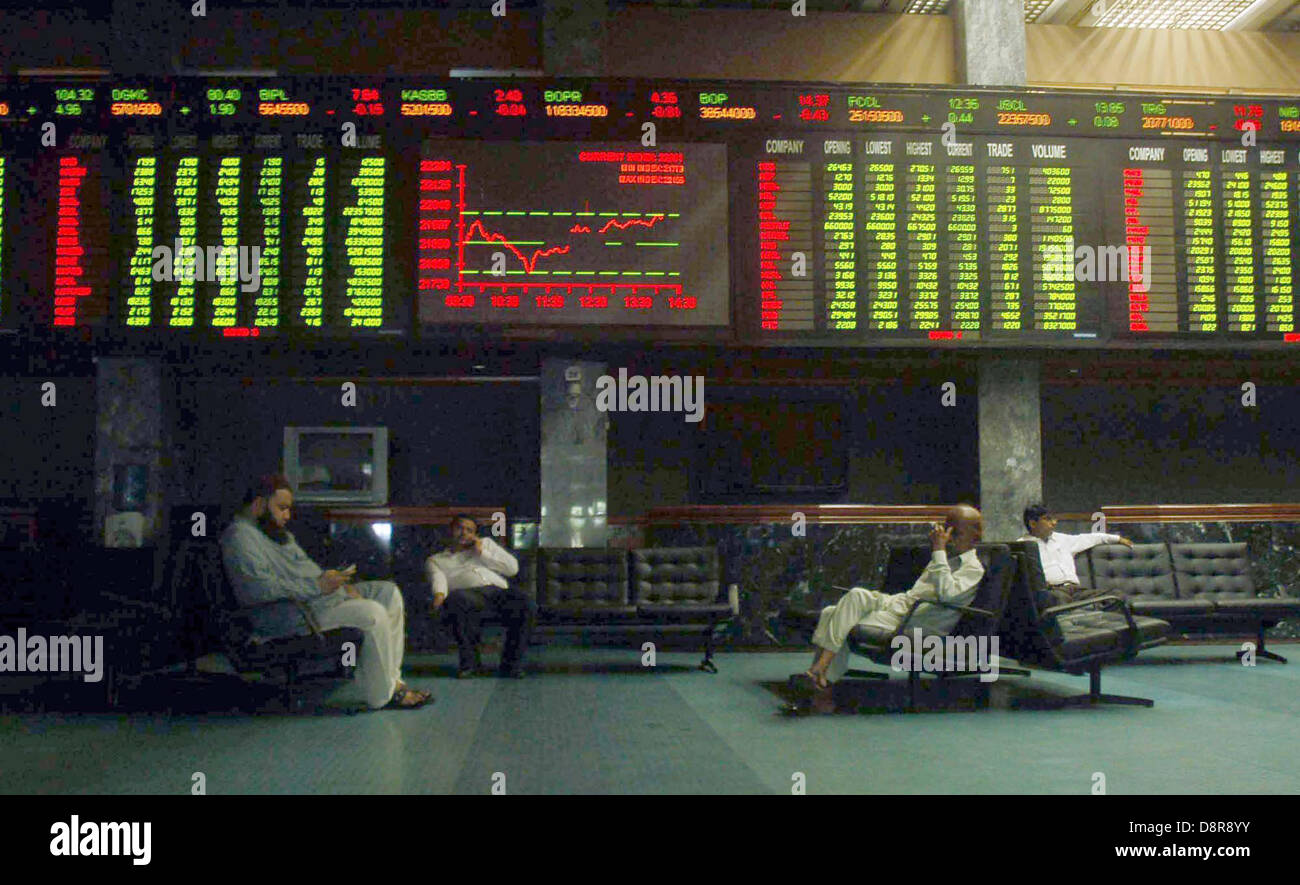 Pakistani traders sit beneath an electronic screen at the Karachi Stock ...
