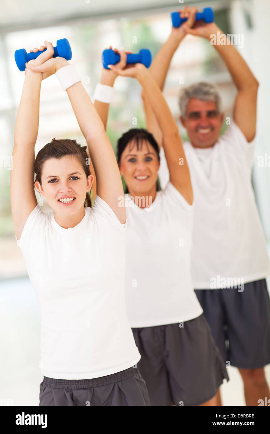 line up of healthy family lifting dumbbells with their daughter in ...