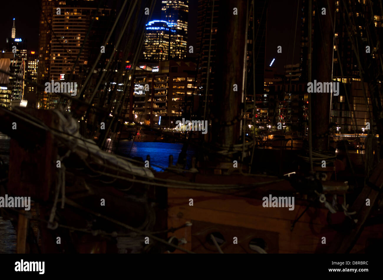 clipper sailing ship moody night light with city lights background ...