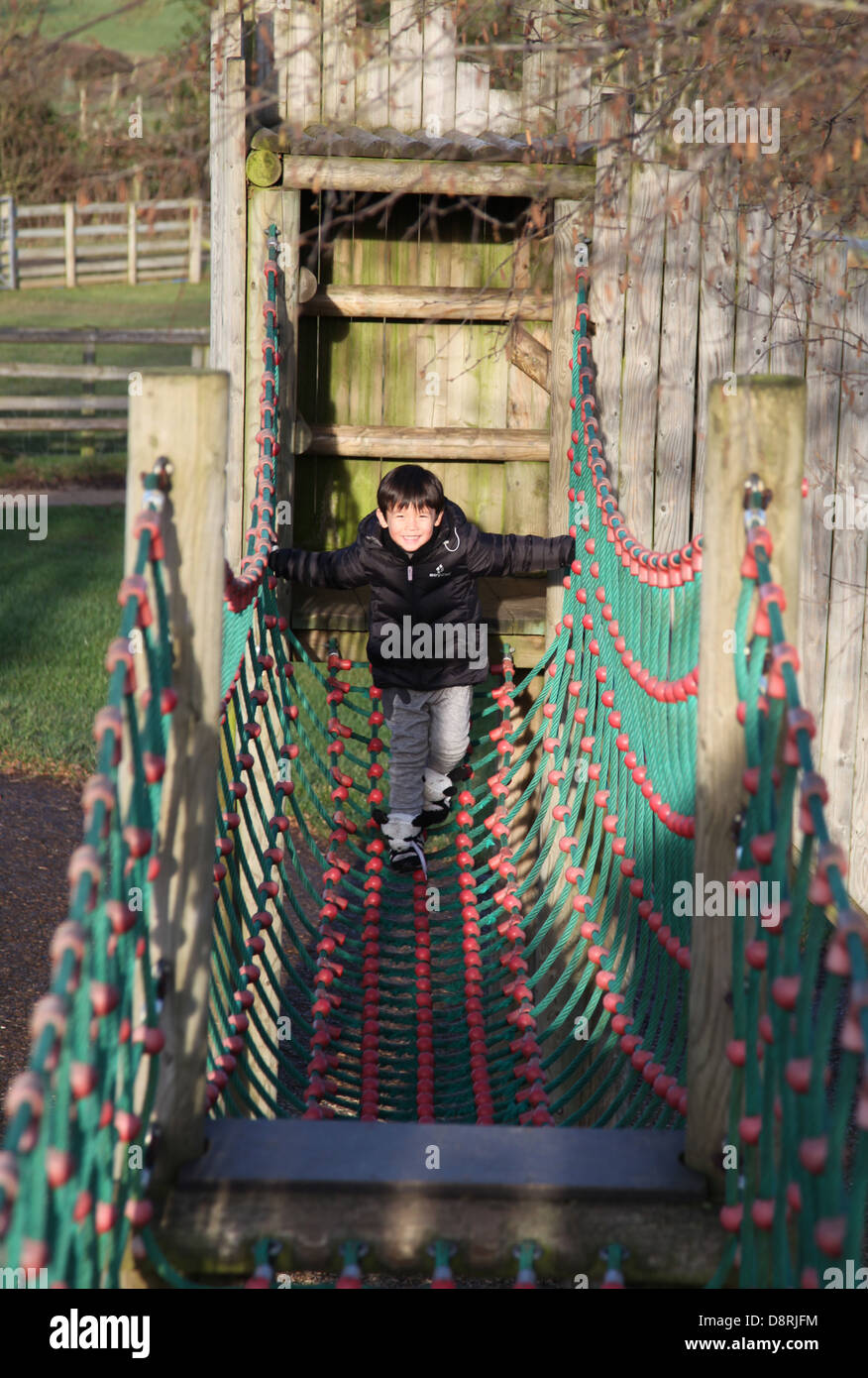 It's a photo of a child boy who is crossing a suspension bridge made of ...