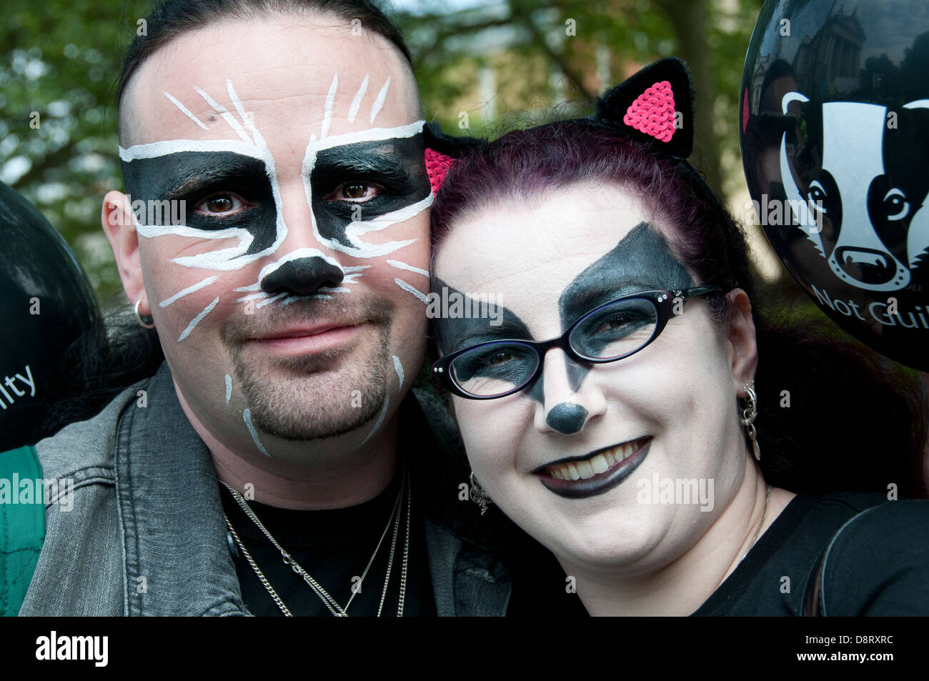 A couple with badger face paint pose holding a balloon with a picture ...