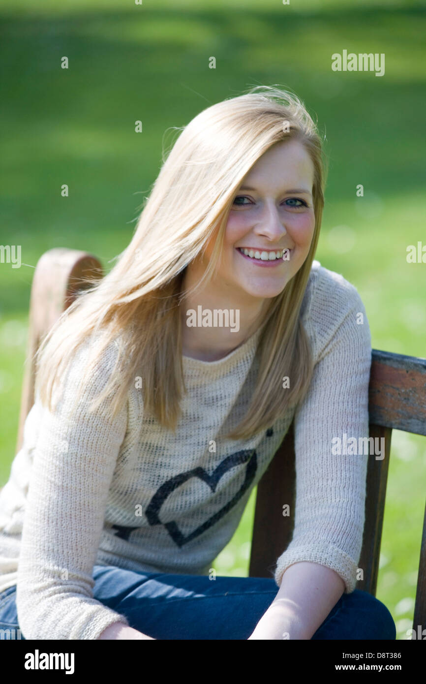 Pretty blonde girl siting on a park bench looking towards camera Stock ...