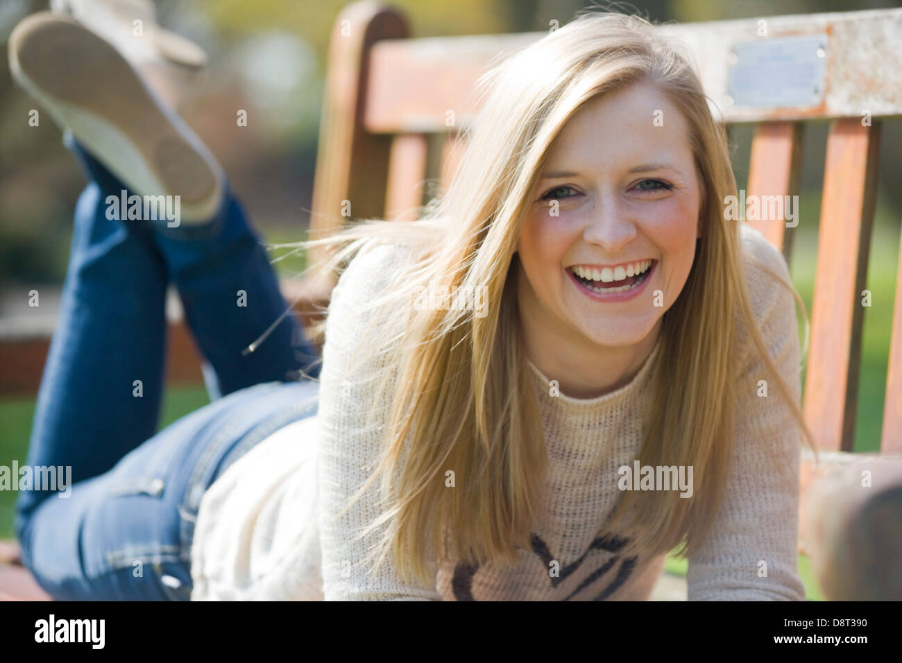 Pretty blonde woman lying down on a park bench on a summers day Stock ...