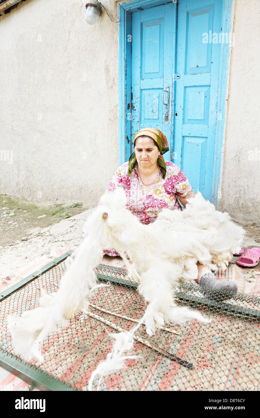 Woman loosening wool with stick Stock Photo - Alamy