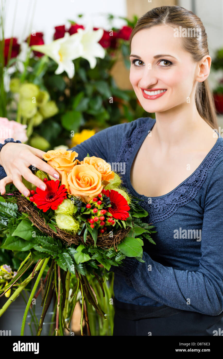 Female florist in flower shop or nursery presenting yellow roses Stock ...