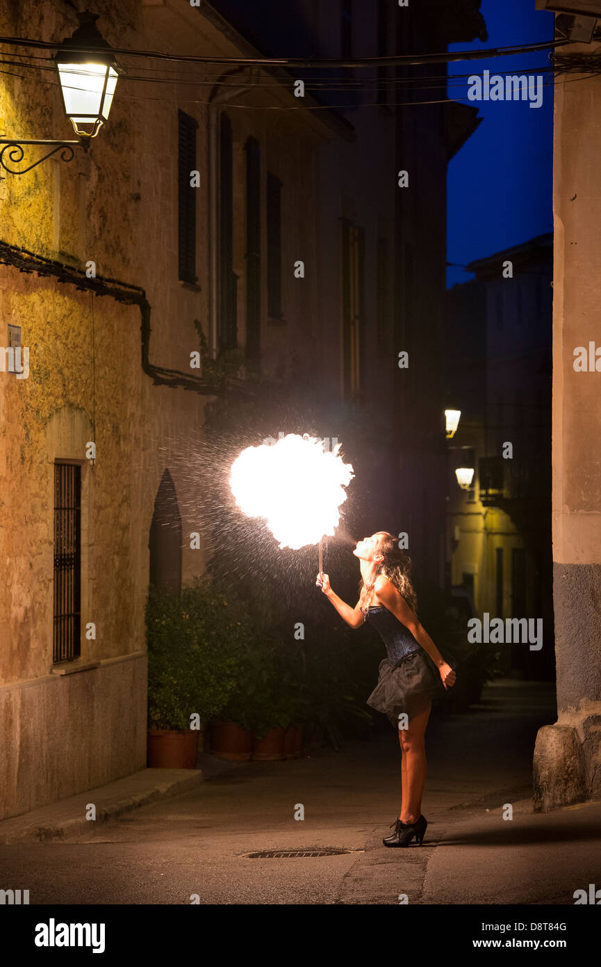 Female fire eater performing at dusk in a street in the old town ...