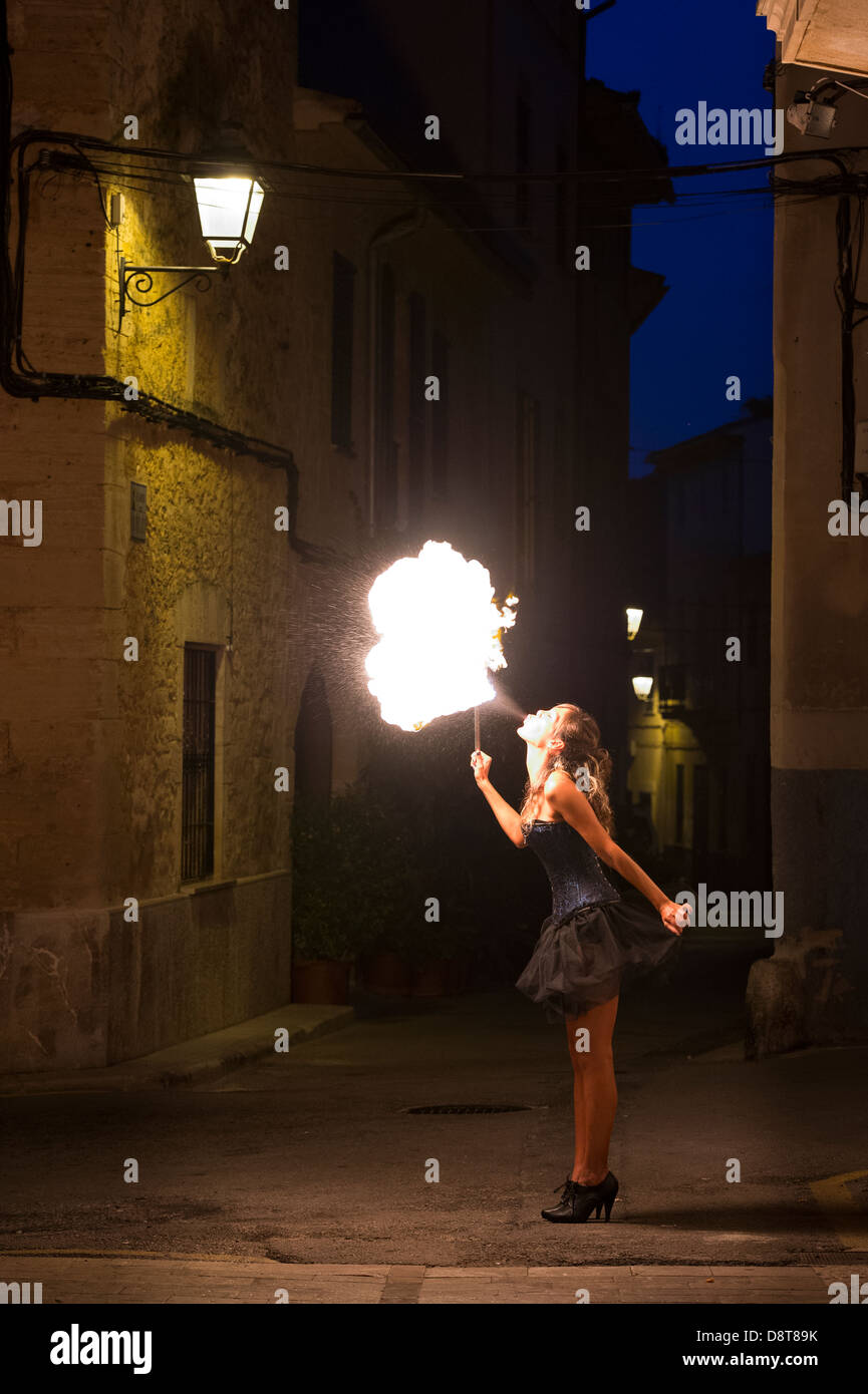 Female fire eater performing at dusk in a street in the old town ...