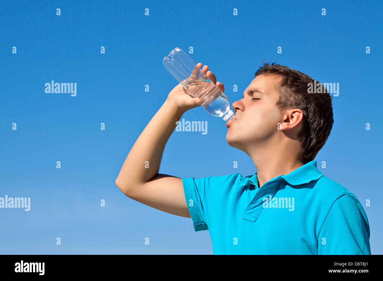 young male drinking water against blue sky Stock Photo - Alamy