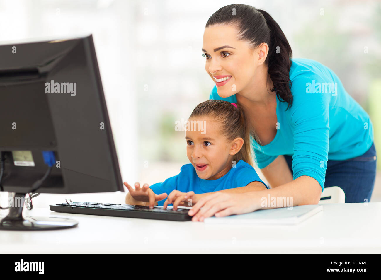 happy young mother teaching daughter computer at home Stock Photo - Alamy
