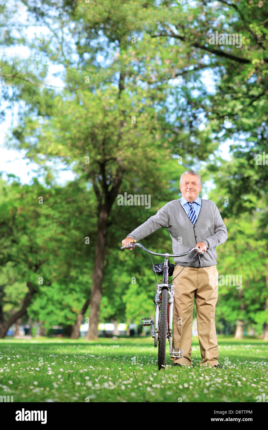 Mature man pushing a bicycle in a park Stock Photo - Alamy