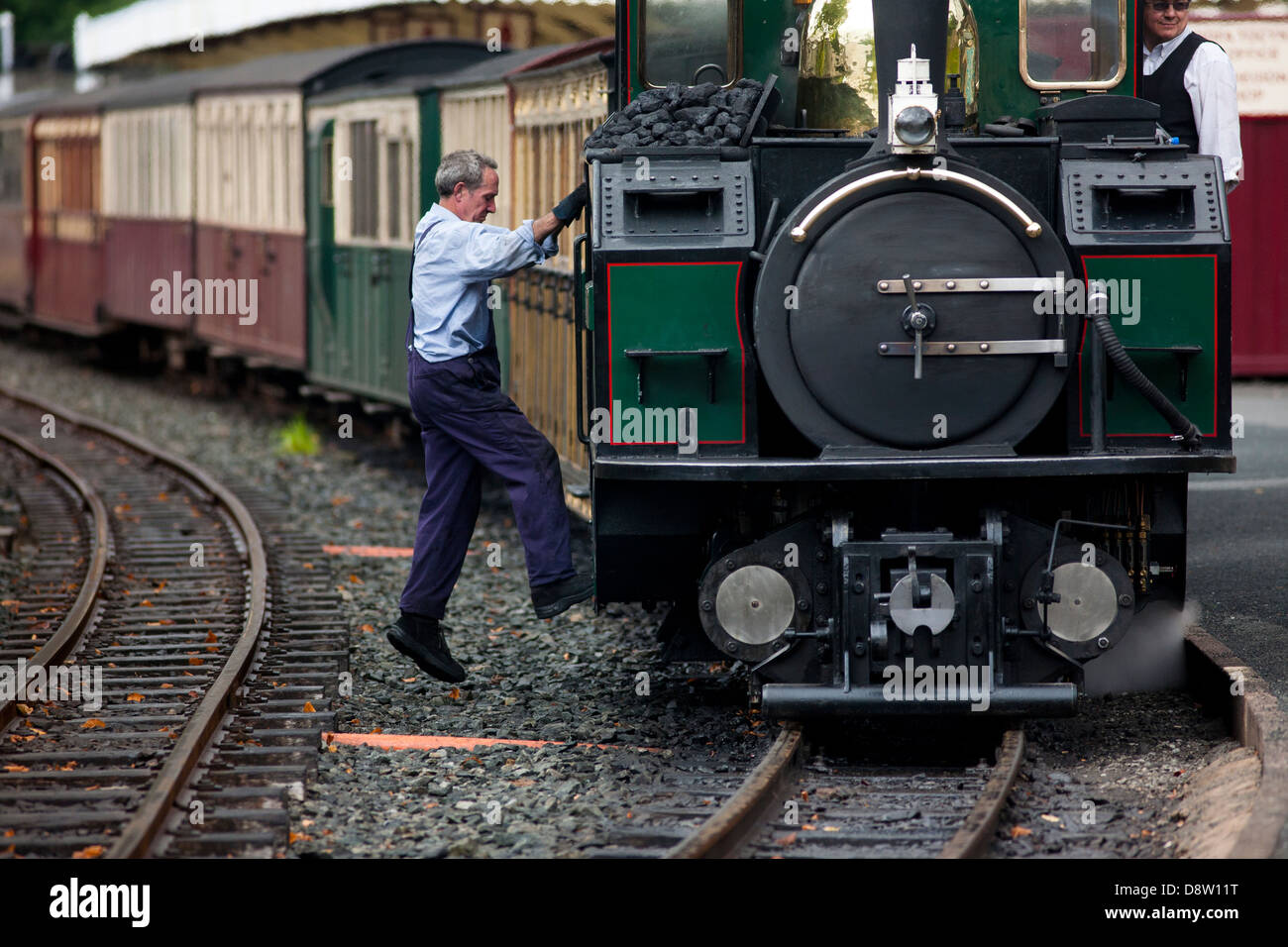The fireman climbs onto the steam engine of Ffestiniog Railway, a ...