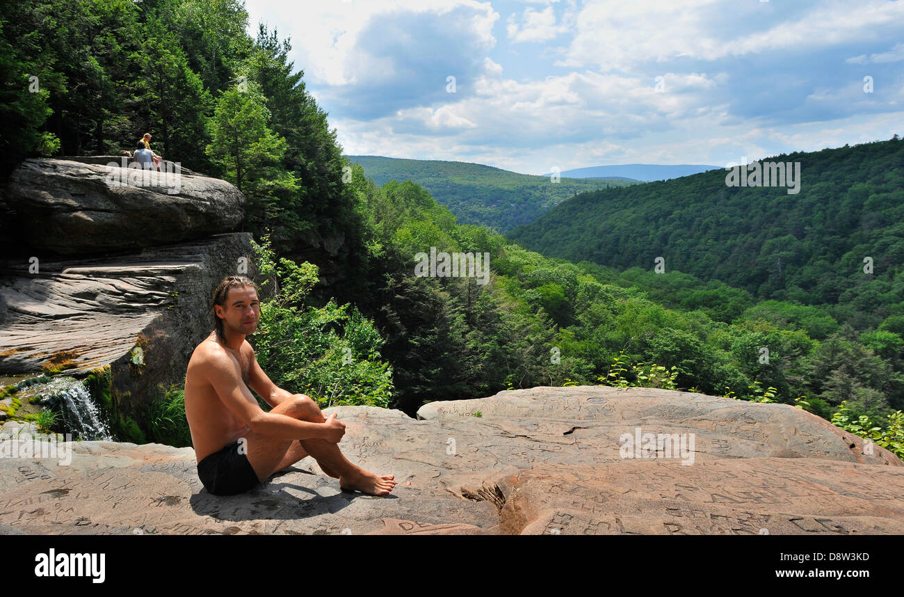A male tourist sits on a boulder ridge overlooking a portion of ...
