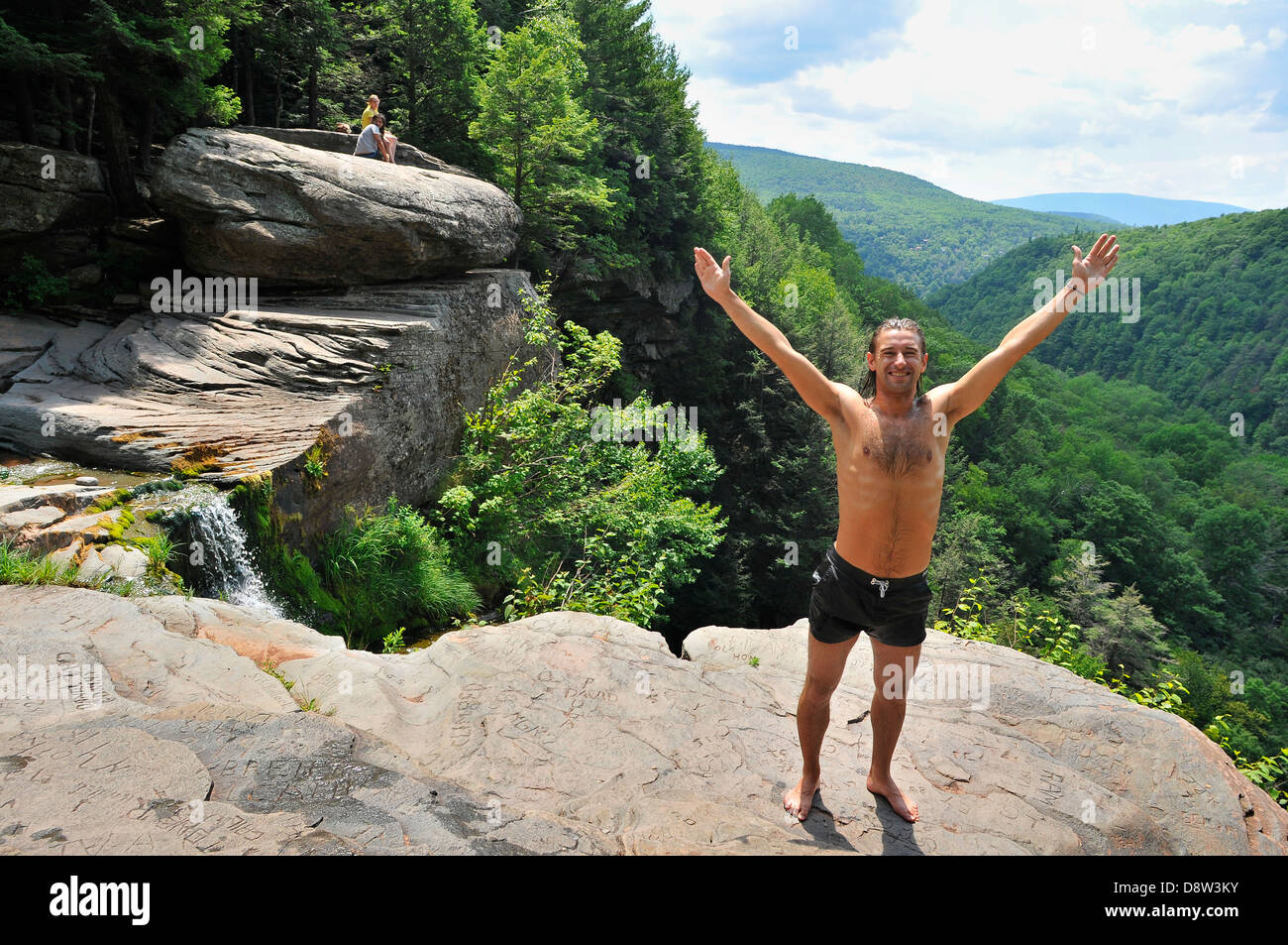 A male tourist stands on a boulder ridge overlooking a portion of ...